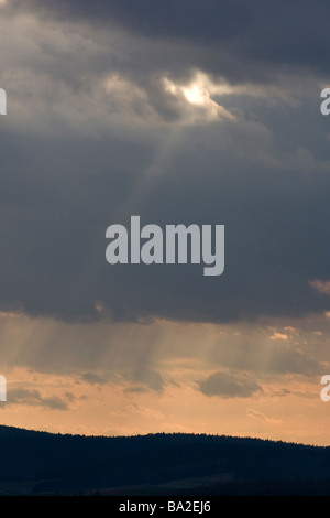 Sunbeam through grey clouds over field Stock Photo - Alamy
