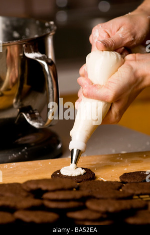Hands of a chef adding dark chocolate cookies to top a creamy chocolate ...