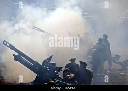 WW2 field guns being fired by crews with smoke blowing back across the ...