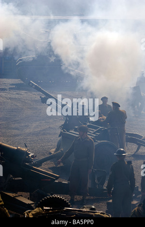 WW2 field guns being fired by crews with smoke blowing back across the ...