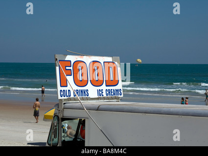 Concession stand advertizes their food items along a busy ocean beach ...