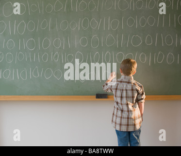 Boy writing binary code on blackboard Stock Photo - Alamy