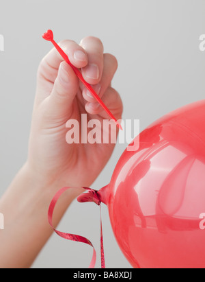 Young woman popping balloon Stock Photo - Alamy