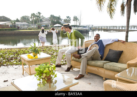 Portrait of 1920s socialite men relaxing at garden party on water's ...