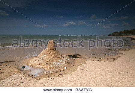 Sandcastle on the beach being washed away by the waves - concept of ...