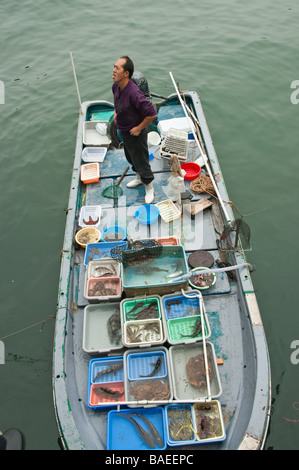 A Chinese fisherman selling fish and seafood from his boat in the ...