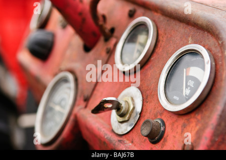 Rusty instrument panel of a red vintage farm tractor showing steering ...