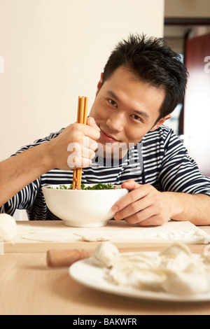 Chinese dumpling held up by chopsticks dipping on soy with black ...