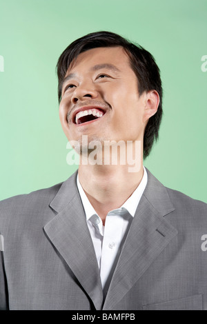 Laughing asian young adult man with copy space on isolated turquoise ...