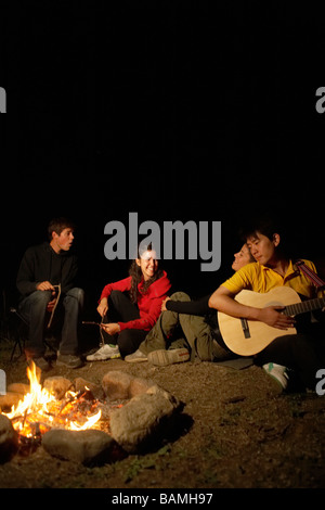 Man is sitting around a campfire and just relaxing, snow on the ground ...