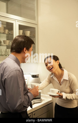 Two office workers with drinks discussing working points by workplace ...