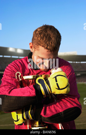Male soccer player triumphantly hugging trophy Stock Photo - Alamy