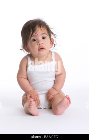 Baby girl (6 months) sitting on floor with mouth open, front view Stock ...