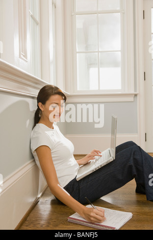 young woman making notes and using laptop Stock Photo - Alamy