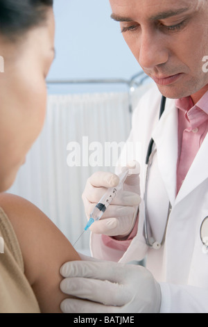 Injection. Doctor administering an injection to a patient's arm Stock ...