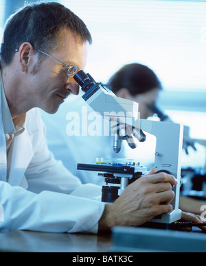 Scientist examining samples under microscope, molecular structure image ...