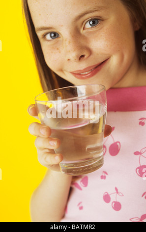 Happy girl with glass of water looking at her friends by served table ...