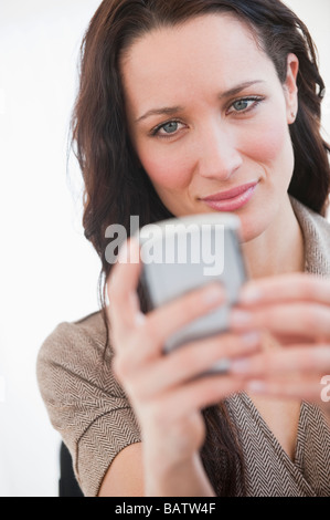Smiling mid adult woman using smartphone while sitting on wooden pier ...