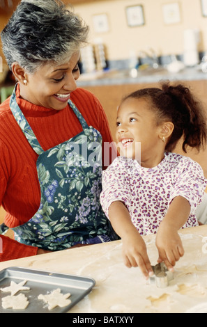 Grandmother and her granddaughter making cookies together at table in ...