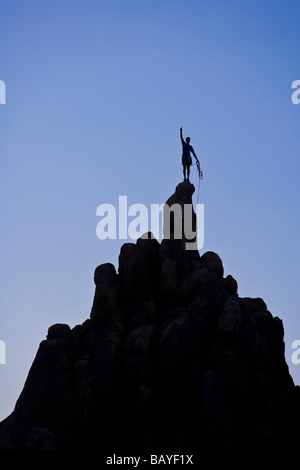 A climber is silhouetted summitting a rock spire Stock Photo - Alamy