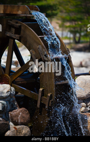 A traditional turning wooden waterwheel motion blurred by a stream next ...