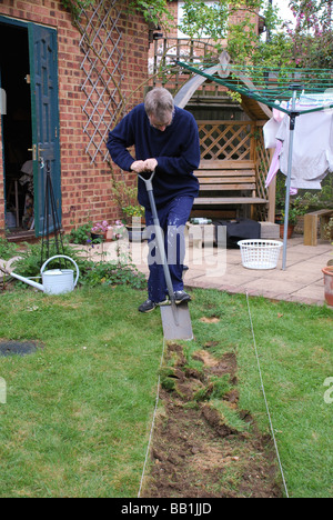 Man digging out turf for new garden path in modern british house Stock ...