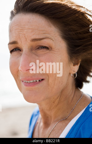 Close up of a mature woman squinting her eye with hand on forehead ...