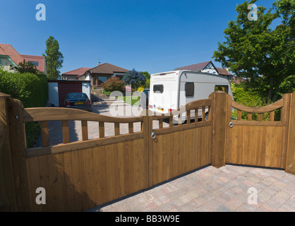 Driveway and garage of detached bungalow with parked cars and caravan ...