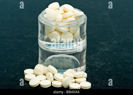 Two clear plastic vitamin containers overflowing with Folic acid ...