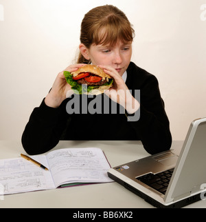 Girl doing homework and eating junk food Stock Photo - Alamy