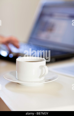 Laptop computer on a table with a cup of tea, a pen, leaves and glasses ...