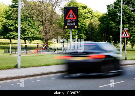 Illuminated converging lanes slow down sign at side of road Stock Photo ...