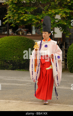 Miko shrine maiden in traditional shinto costume at Shimon main gate, Kumano Hongu Taisha, world ...