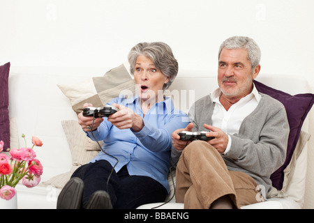 Cute man and woman playing game by joysticks on sofa at home Stock ...