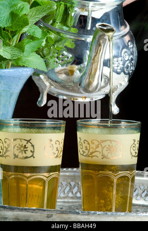 Pouring of hot Turkish tea from teapot into glass on wooden table ...
