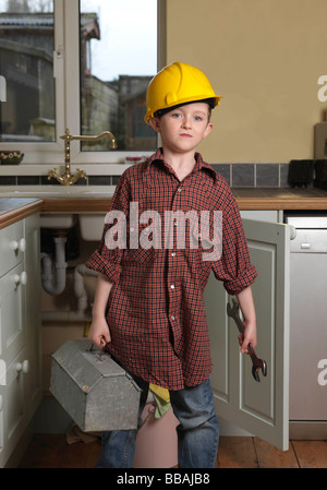 Industrious young boy repairing one of his toys in a home kitchen ...