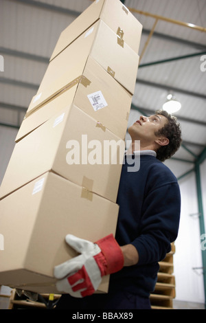 Young man carrying a box to the pile of boxes Stock Photo - Alamy