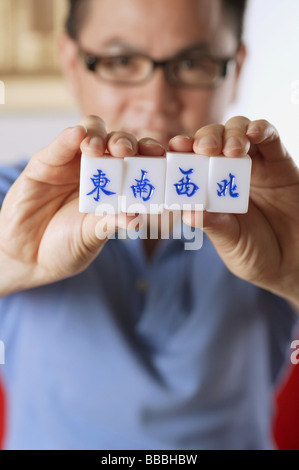 Man holding mahjong tiles with Chinese characters for One, Six and ...
