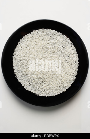 Uncooked white rice grains are spread out closely, showcasing their ...