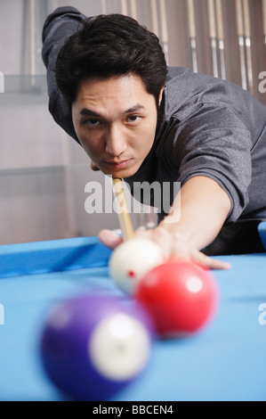 Man holding pool cue, aiming at ball Stock Photo - Alamy