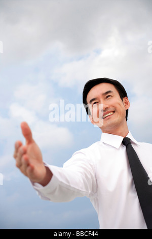 Businessman, hand outstretched, smiling Stock Photo - Alamy