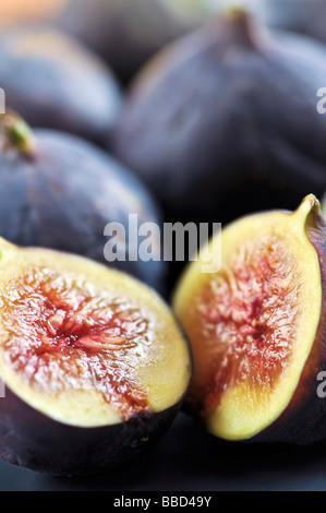 whole and sliced ripe fresh figs on a black table. close-up. the fruit ...