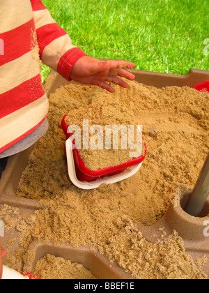 Close-up of a boy digging with a bucket in the garden for planting a ...