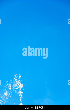 Water jet of a fountain against sunny blue sky in short-time-exposure ...