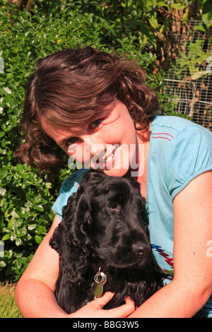 A girl pets her cocker spaniel dog on the street in a green park. Pets ...