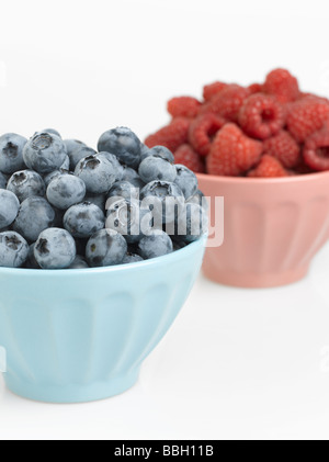 Bowls of blueberries and raspberries isolated on a yellow background ...