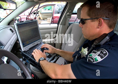 Police officer using a mobile data terminal computer inside a police ...