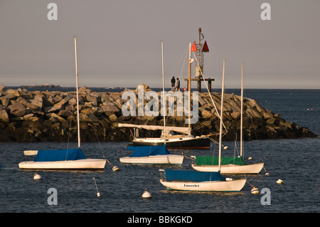Sailboats in Rockport Outer Harbor in the evening. Two people on jetty ...