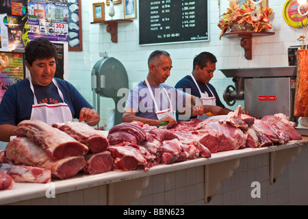 2 Mexican butchers cutting and cleaning meat in a butcher shop at the ...