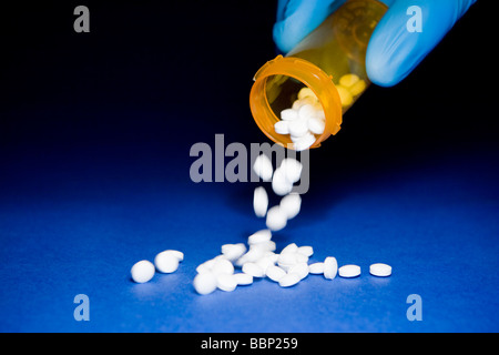 Close up of white pills spilling from orange container Stock Photo - Alamy